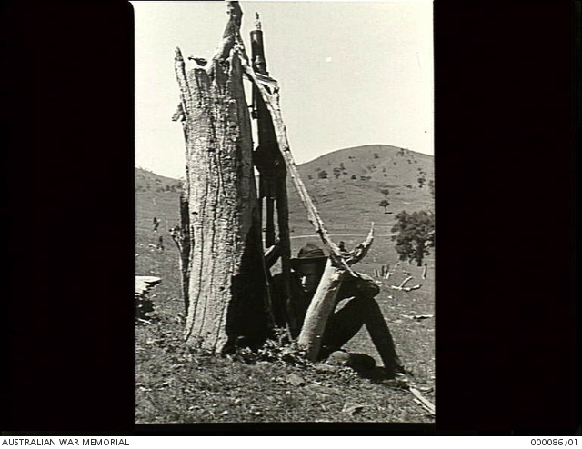 A gunner crouches behind an anti aircraft Lewis gun camouflaged in an ...