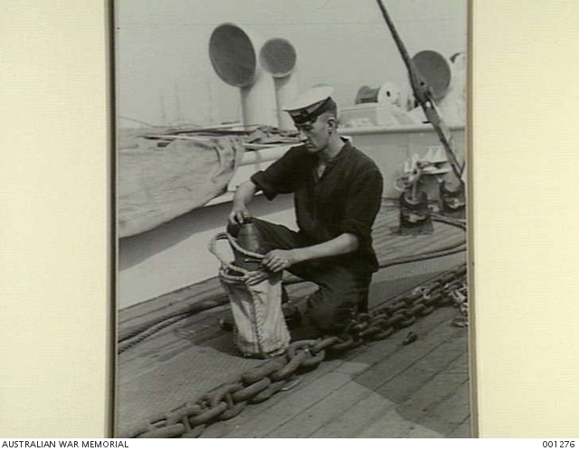 A rating examines the fuse of a shell brought aboard the Armed Merchant ...