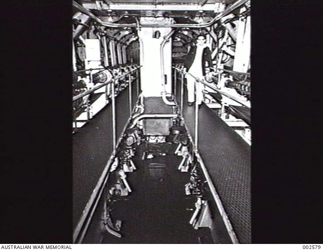 AN UNIDENTIFIED CREW MEMBER IN THE ENGINE ROOM OF THE 2/1ST AUSTRALIAN ...