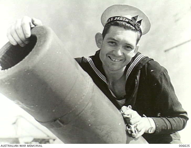 A CREW MEMBER OF HMAS PERTH CLEANING ONE OF THE SHIP'S 6-INCH GUNS ...