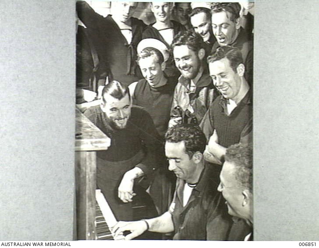A GROUP OF SAILORS ON HMAS PERTH ENJOYING THEMSELVES AROUND A PIANO ...