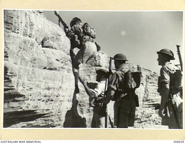 A.I.F. IN PALESTINE. BEING PULLED OVER LOW CLIFF BY RIFLE OF MEN ABOVE ...