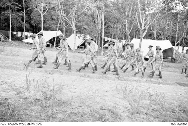 Malaya. Members of the 8th Division AIF, march into camp after ...