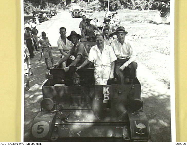 RIDING ON A BREN GUN CARRIER THROUGH A NATIVE VILLAGE IN MALAYA. AUST ...