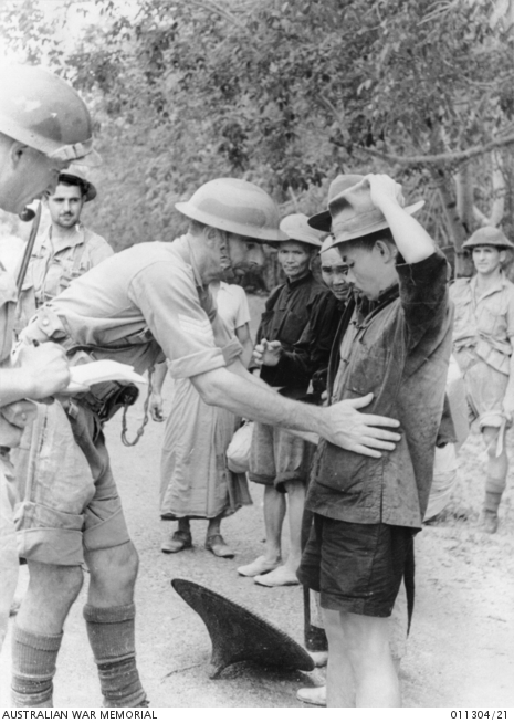 MALAYA. AN AUSTRALIAN SERGEANT OF THE 8TH DIVISION CHECKING A CIVILIAN ...