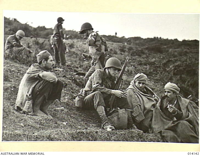 AN AMERICAN SOLDIER TALKING TO THREE ARABS WHILE WAITING TO MOVE OFF ...