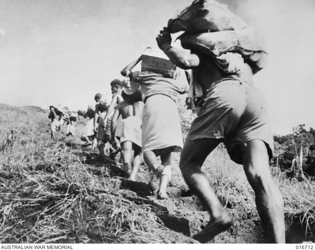 New Guinea. Local native carriers wending their way up the steep ...