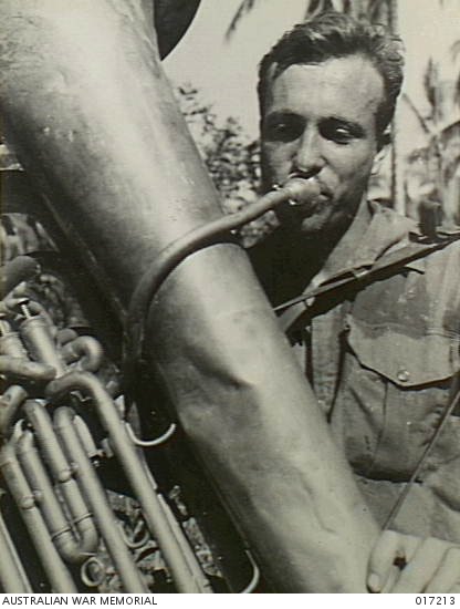 New Guinea. Private C. R. Gazzard of Parramatta, NSW, blowing on the ...