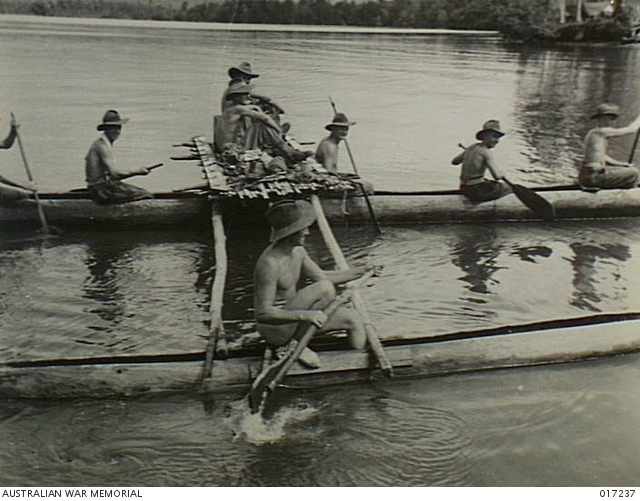 New Guinea. Lending a hand to propel the lakatoi (native canoe), is ...