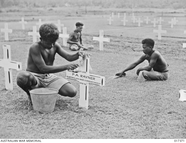 A Papuan boy is washing the white cross over the grave of the late C ...