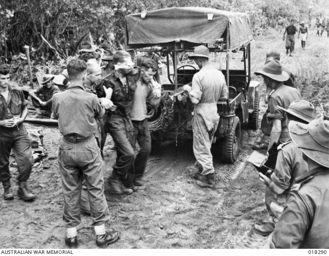Aitape Sector, New Guinea. Being helped to a jeep-ambulance on a ...