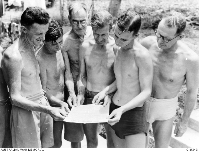 Probably Singapore. c. 1945. Internees from Sime Road Camp read their ...