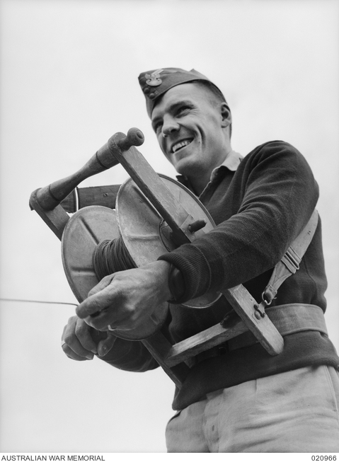A Polish signalman in Tobruk uncoiling wire. | Australian War Memorial