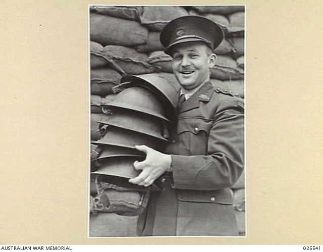 MIDDLE EAST. 1941. AN AUSTRALIAN CAPTAIN SMILES AS HE CARRIES AN ISSUE ...
