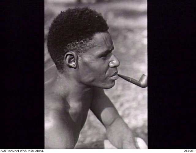 BUKAUA, NEW GUINEA. 1943-10-18. PORTRAIT OF MAGASI WITH A PIPE IN HIS ...