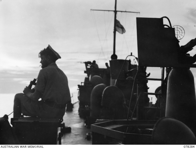AT SEA. 1945-01-01. ABLE SEAMAN V. PRANCE, ON THE DAWN WATCH, RELAXES ...
