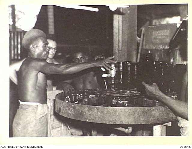 LAE, NEW GUINEA. 1944-12-12. NATIVES SUPPLIED BY ANGAU WORK UNDER THE ...