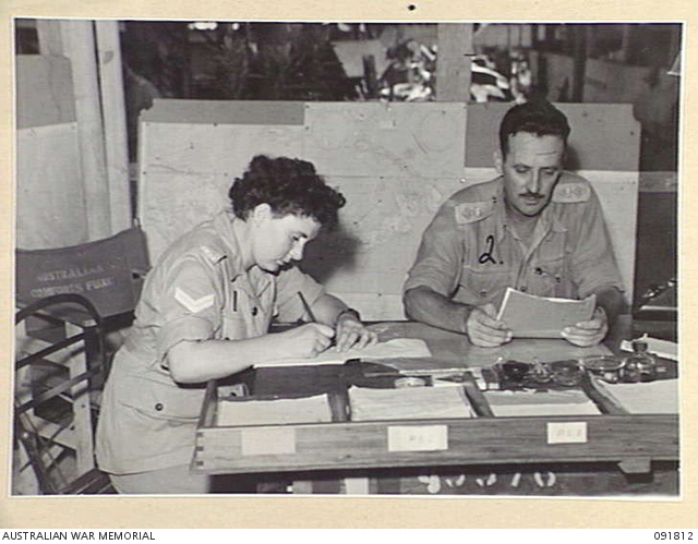 LAE, NEW GUINEA. 1945-05-15. CORPORAL M. HARVEY (1), TAKING DICTATION ...