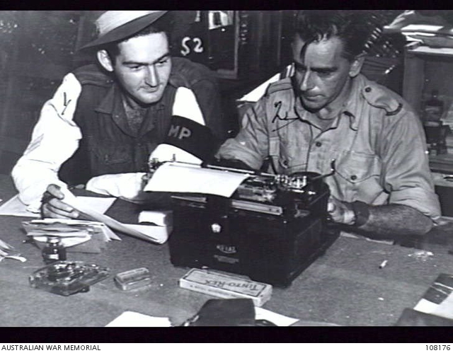 MOROTAI, 1945-05-25. SERGEANT A.R. WATTS (1) WATCHING HIS REPORT BEING ...