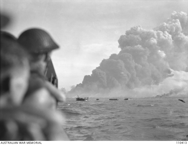 OFF BALIKPAPAN, BORNEO. 1 JULY 1945. DENSE CLOUDS OF BLACK SMOKE RISING ...