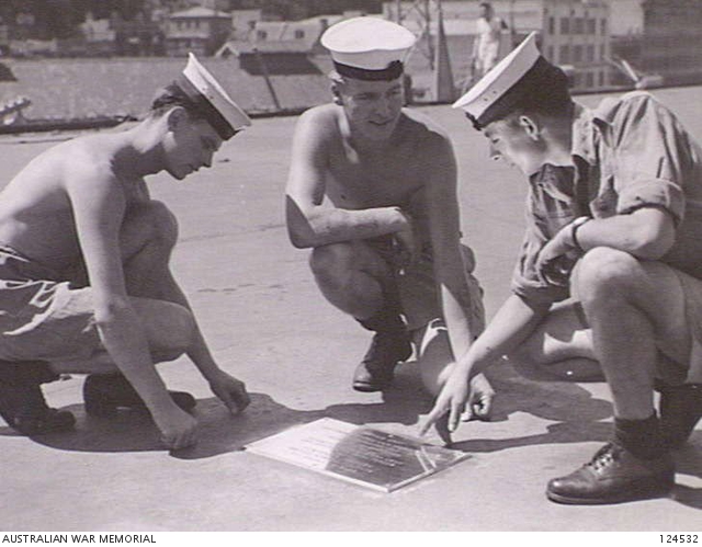 SYDNEY, NSW. 1945-12-23. THREE BRITISH SAILORS EXAMINING THE PLAQUE ...