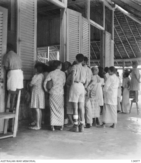 AMBON 1946-01-03. AMBONESE GATHERED ROUND THE DOORS AND WINDOWS OF THE ...