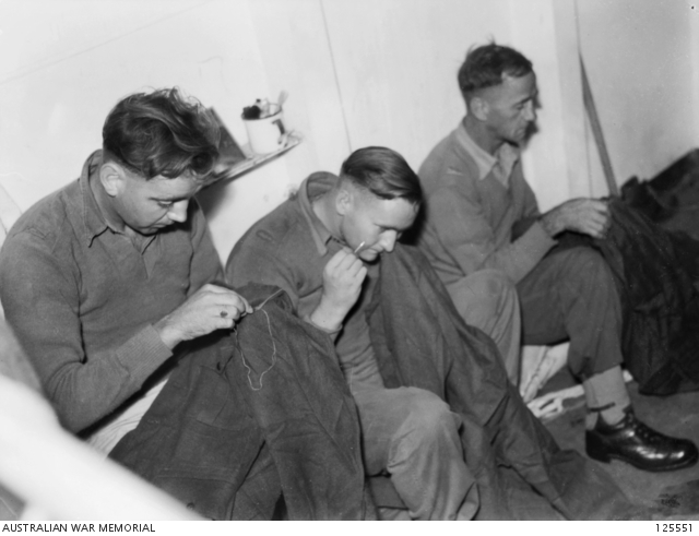 AT SEA OFF JAPAN. 1946-02-12. SOLDIERS SEWING THEIR NEW UNIT COLOUR ...