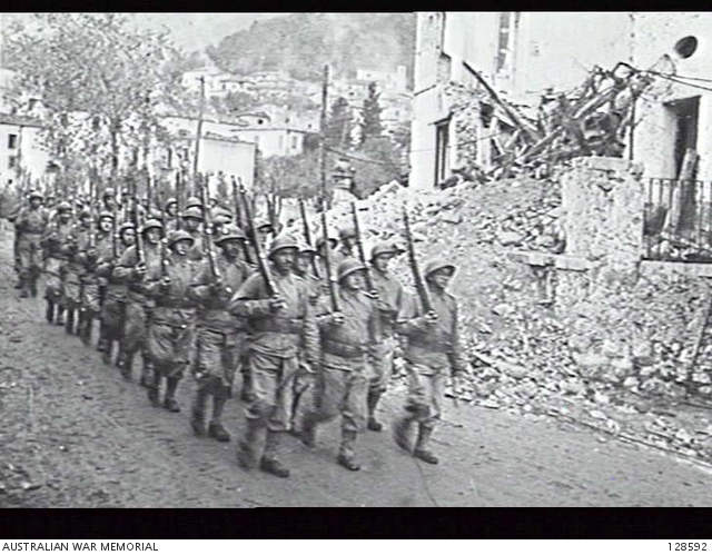 ITALY. 1944-01. FRENCH TROOPS MARCHING THROUGH A RUBBLE-LINED STREET ...