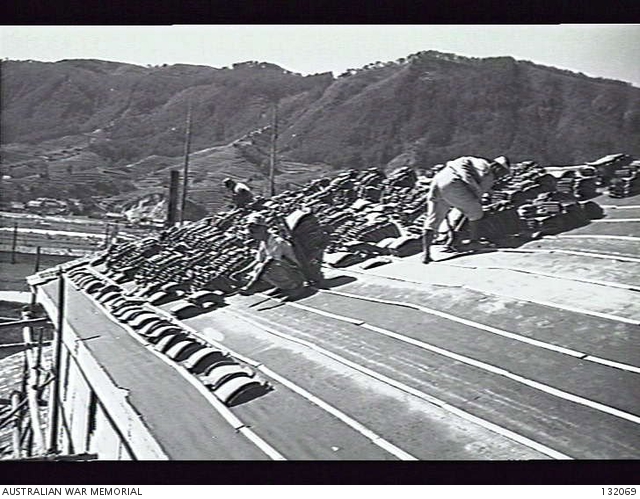 HIRO, JAPAN. 1946-01-10. JAPANESE LABOURERS UNLOADING TILES ON THE ROOF ...