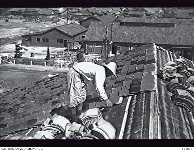 HIRO, JAPAN. 1946-01-10. A JAPANESE LABOURER TILING THE ROOF OF ONE OF ...