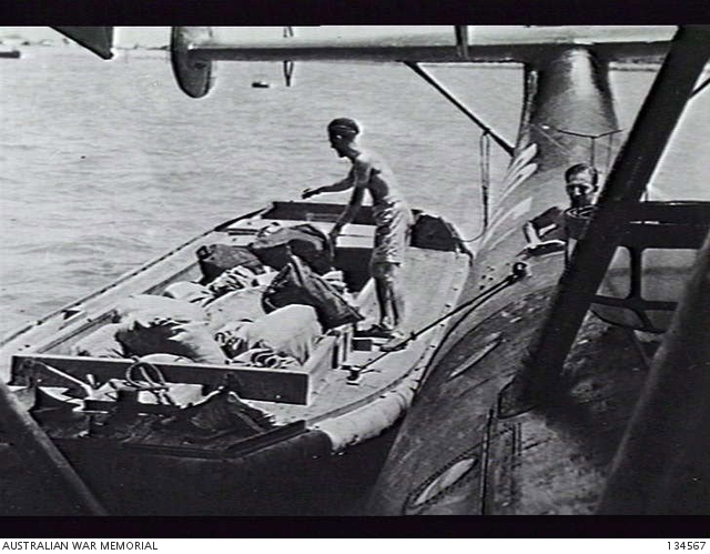 BOMB SCOW, RAAF TYPE 010-, BEING LOADED WITH MAIL FROM A SEAPLANE AT A ...