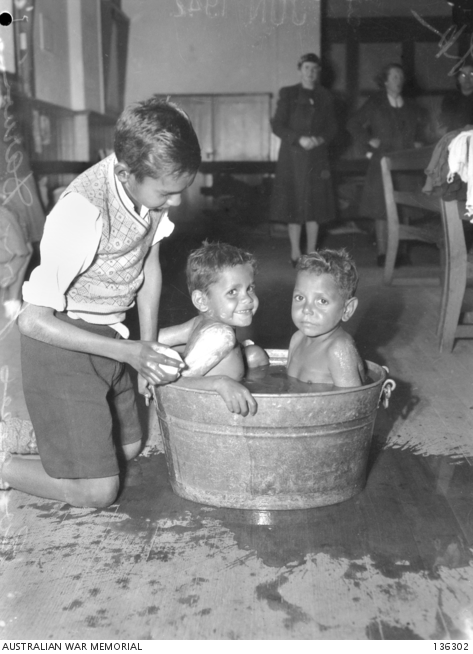 MELBOURNE, VIC. 1942-06-03. AN ABORIGINAL BOY BATHING TWO OF HIS FELLOW ...