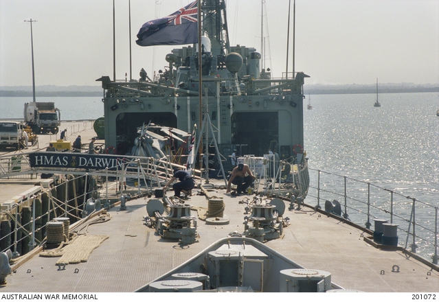 Loading a Sea Hawk helicopter onto HMAS Darwin, prior to its departure ...