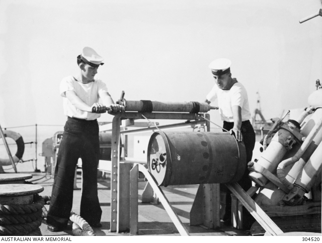 C.1950. A DEPTH CHARGE BEING PARBUCKLED ONTO THE RUNWAY ABOARD THE ...