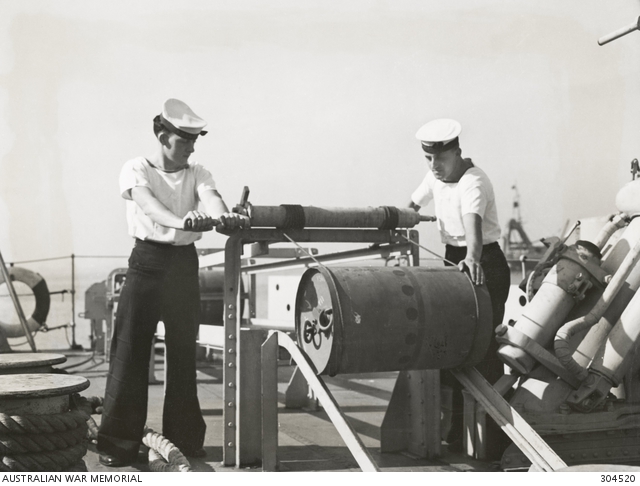 C.1950. A DEPTH CHARGE BEING PARBUCKLED ONTO THE RUNWAY ABOARD THE ...