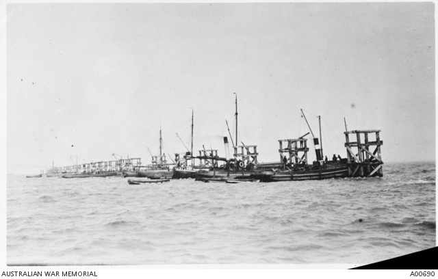 Engineers on barges using pile drivers to construct boom defence works ...