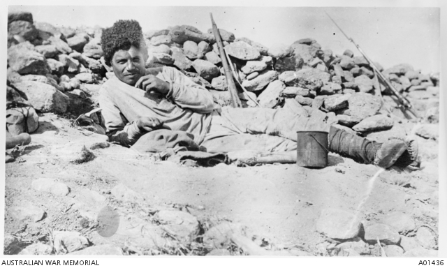 An Armenian soldier lying in a 'trench'. Two rifles are lying against ...