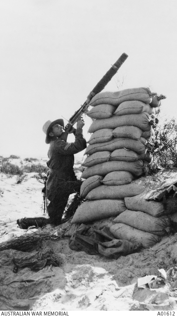 A soldier firing a Lewis gun over a parapet of sandbags at an enemy ...