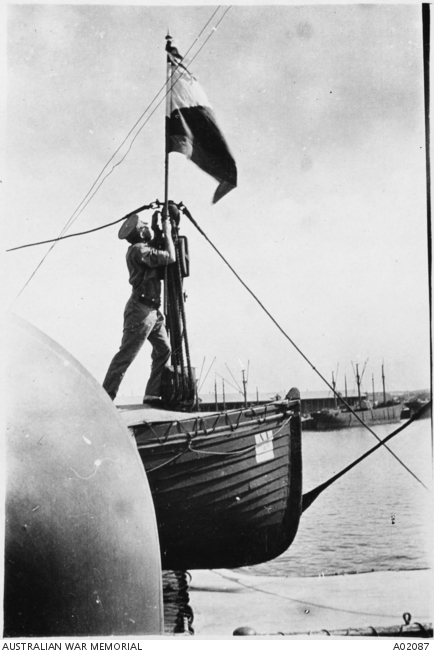 Hoisting the flag at Fremantle. Ships are in the background ...