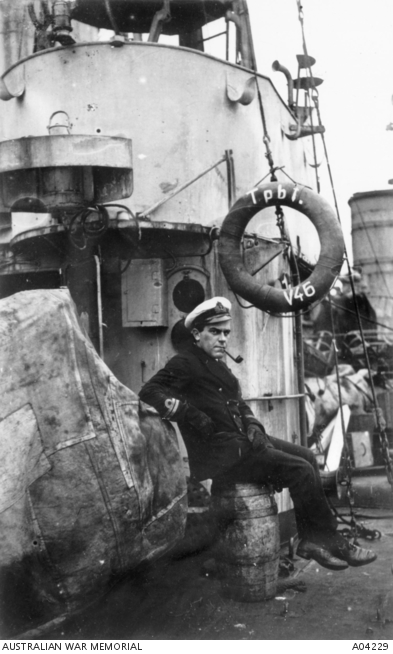 Lieutenant Commander Watson, seated on a barrel smoking a pipe, on ...