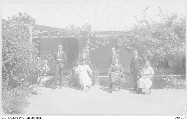 Outdoors portrait of C E W Bean and staff. Standing left to right, back ...