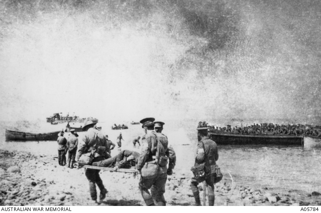Stretcher bearers carry a wounded soldier to waiting barges loaded with ...