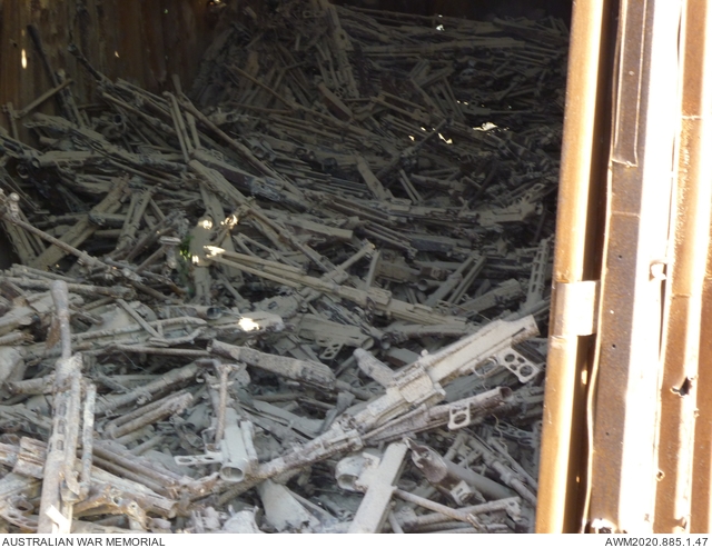 Broken weapons spill out of shipping containers in the ruins of Qala-i ...
