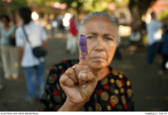 A woman shows her inked finger after casting her vote during the first ...
