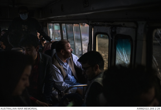 A mini-bus convoy loaded with more than 100 Afghan evacuees drives ...