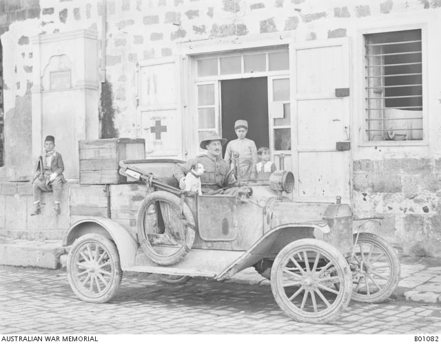 A motor car with a driver and his mate, a dog, delivering cases of Red ...