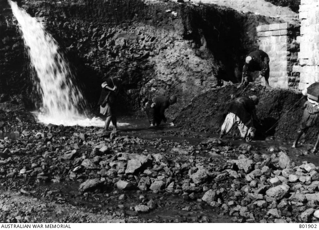 Four local men digging in front of a waterfall, possibly diverting the ...