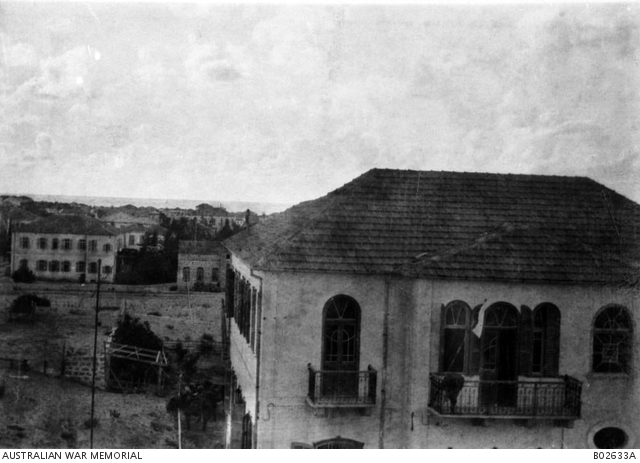 A view of Jaffa. A soldier is leaning over the balcony of a building ...