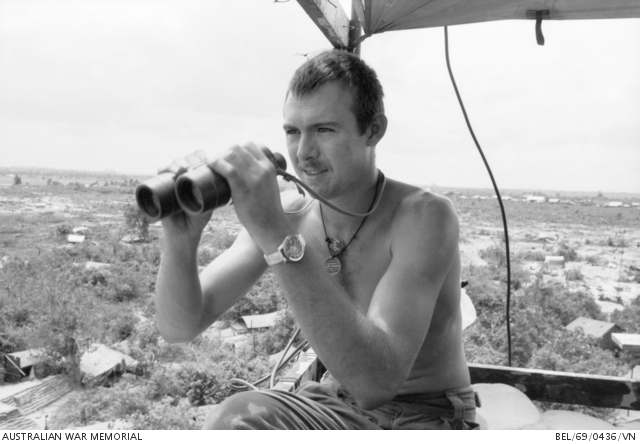 Bare-chested Gunner Ted Robinson of Nambour, Qld, looking through ...