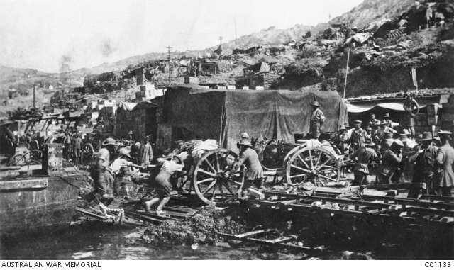 Soldiers push two field guns along after taking them from a barge onto ...